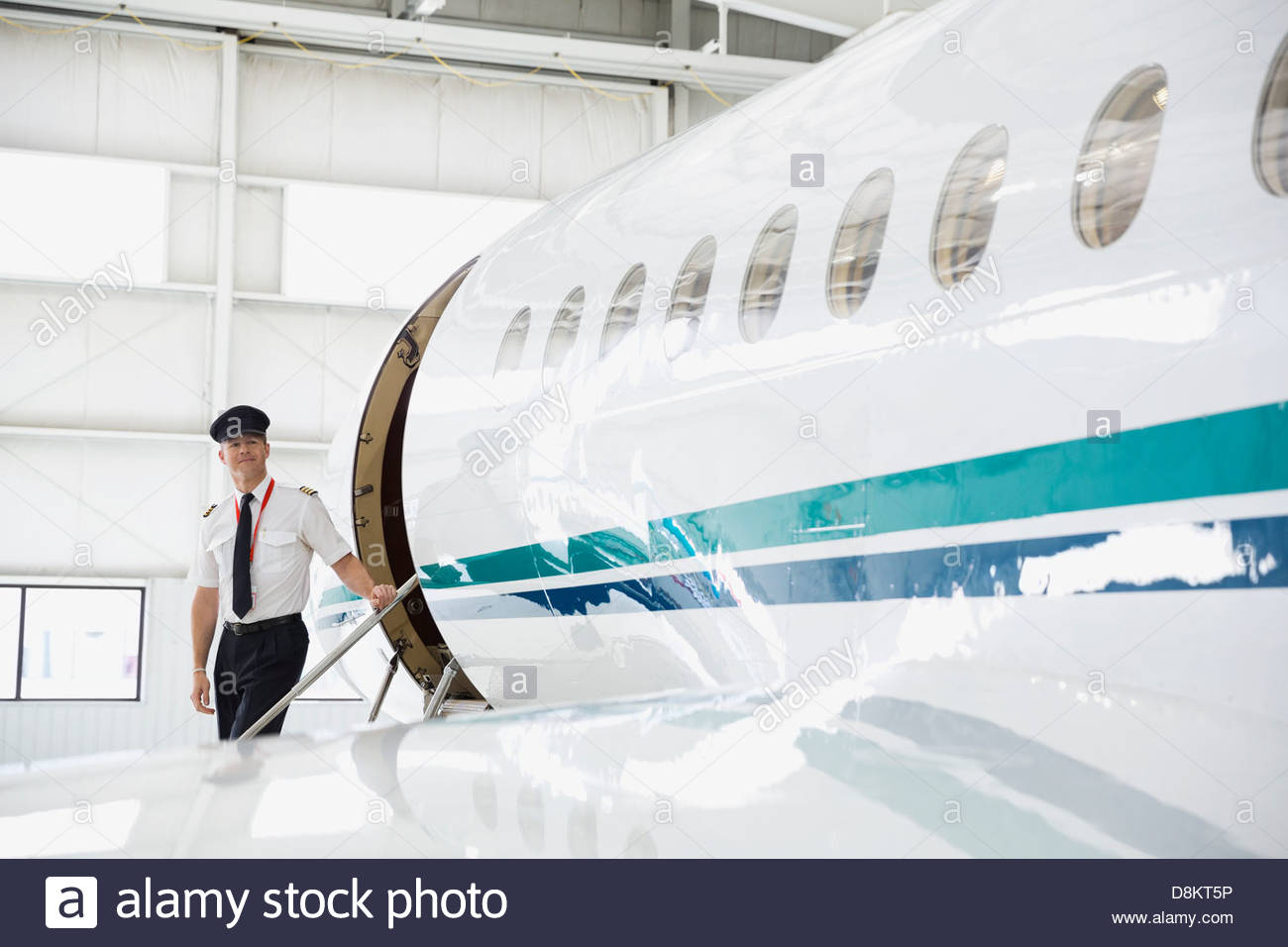 Smiling male pilot deboarding plane in hangar Stock Photo - Alamy