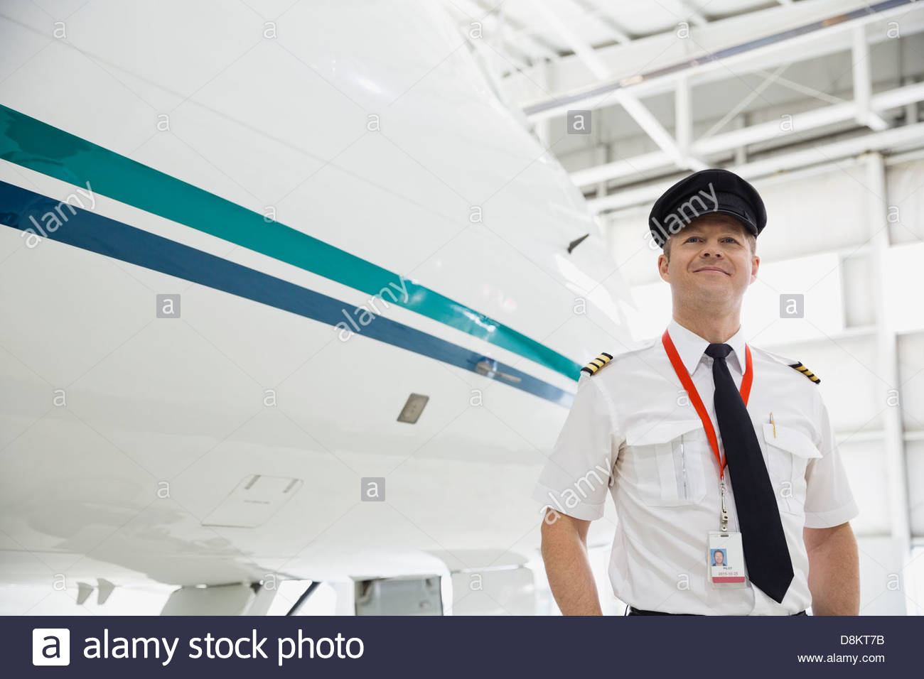 Male pilot standing by airplane in hangar Stock Photo - Alamy
