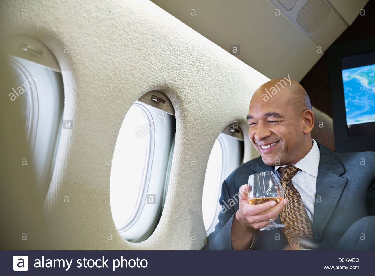 Businessman relaxing with a drink in private jet Stock Photo - Alamy