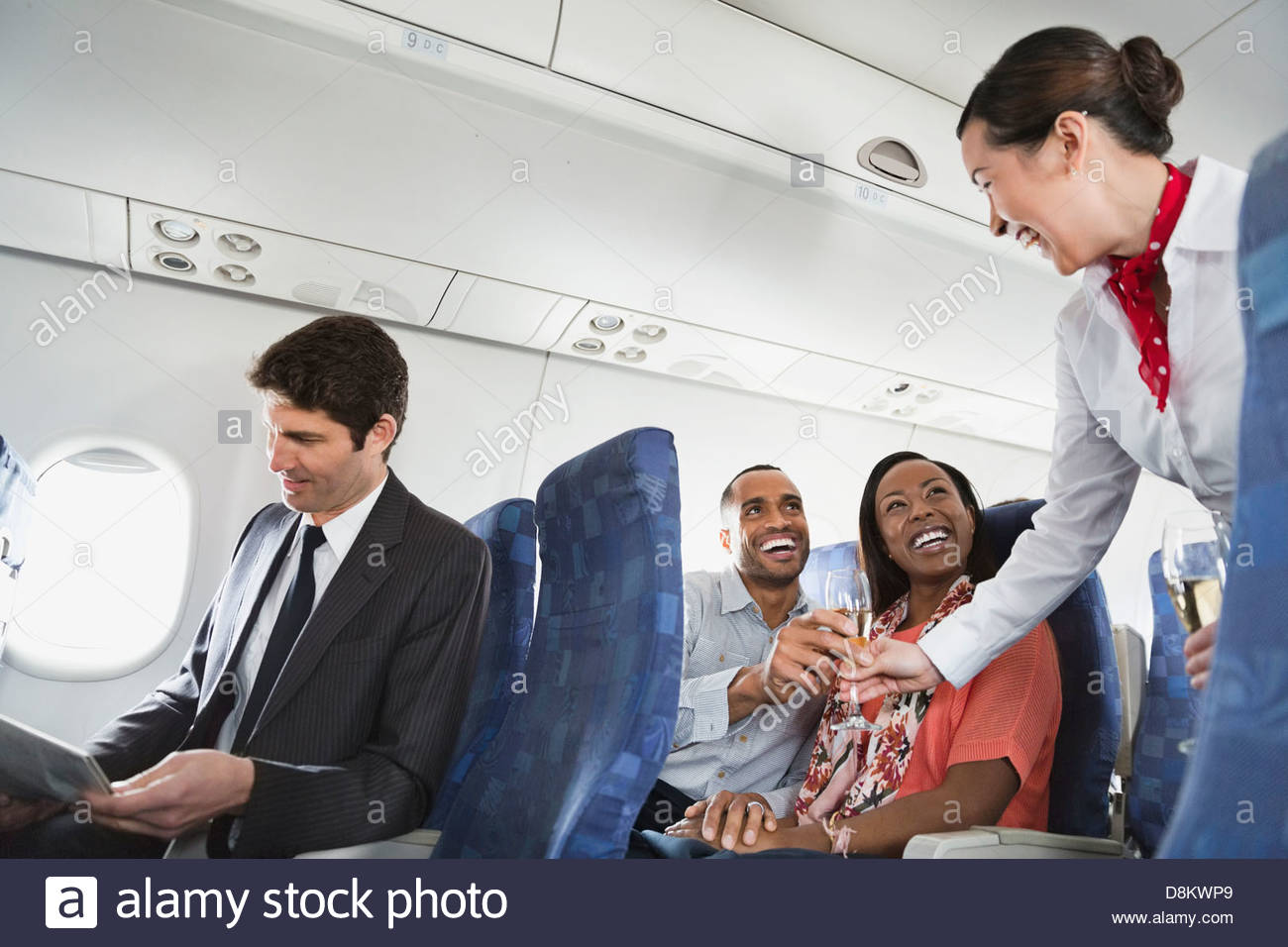 Smiling flight attendant serving drinks to passengers Stock Photo ...