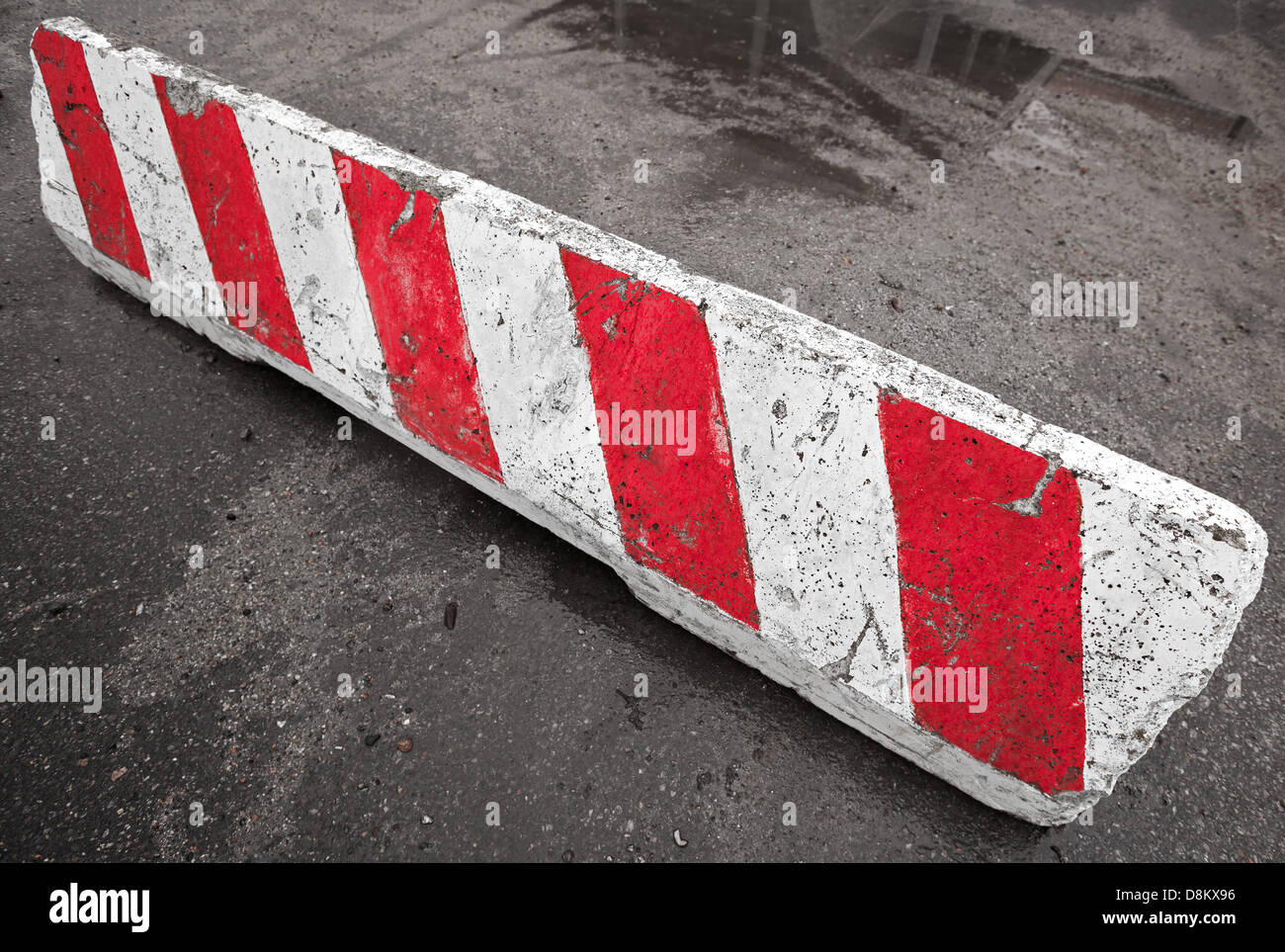 Red and white striped concrete road barrier lying on the pavement Stock ...
