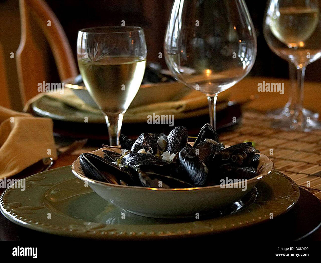 A plate of steamed mussels served on a dinner table, surrounded by ...