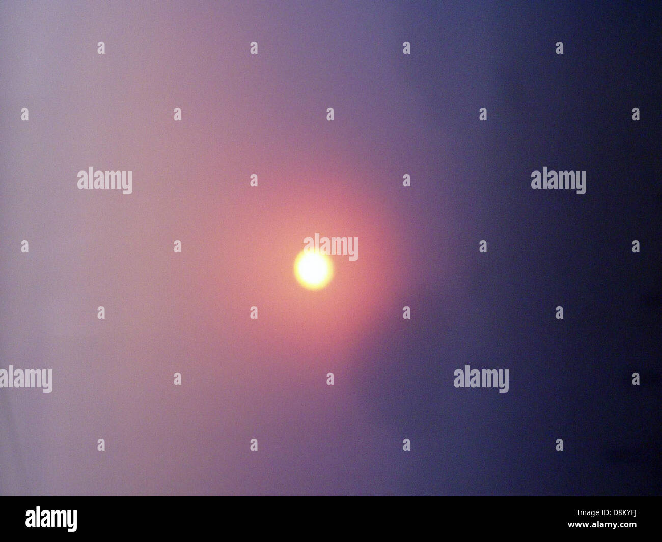 The sun peeking through a thick layer of fog, creating a diffused light ...