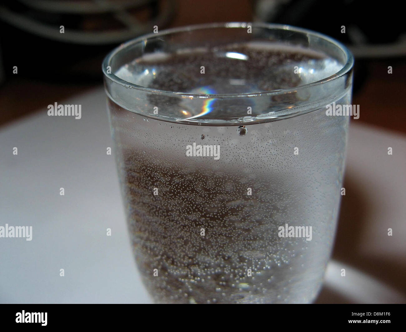 The image shows a clear drink in a glass, capturing its transparency ...