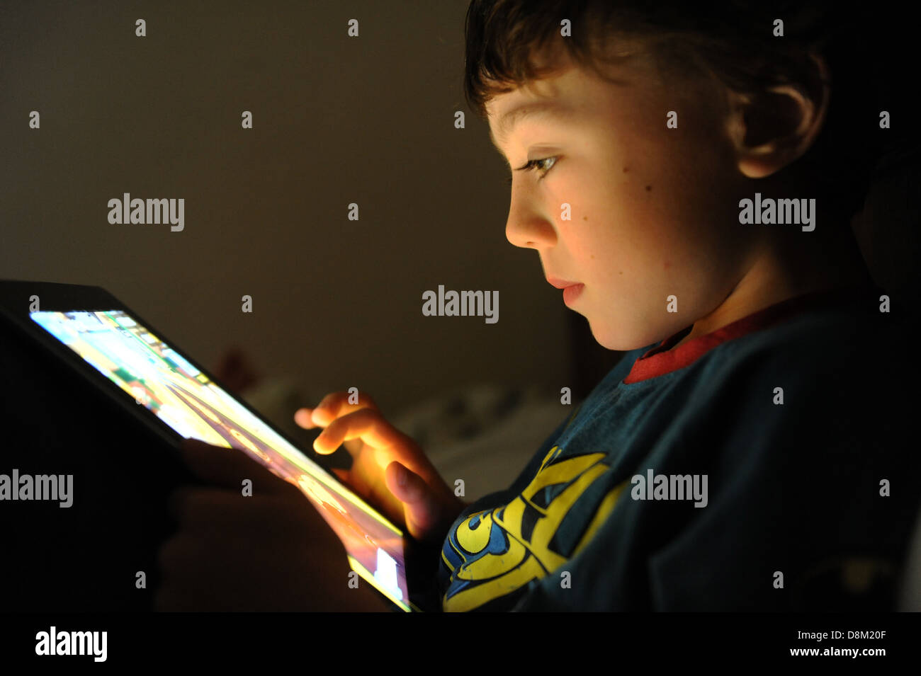 An 8 year old boy playing a computer game on his Apple IPAD in his ...