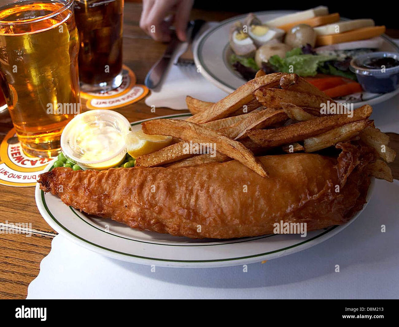 A plate of fish and chips served with a pint of cider, a traditional ...