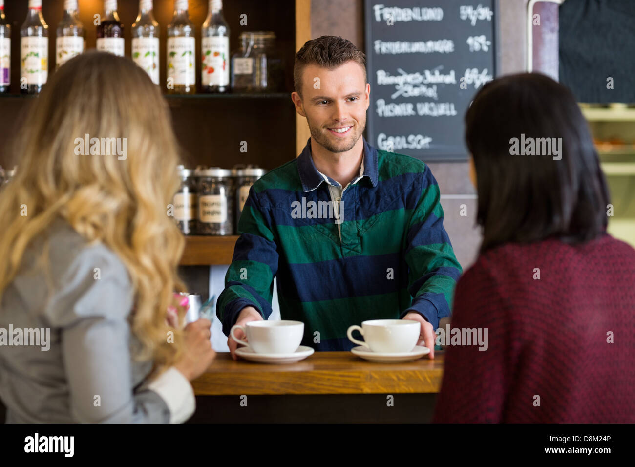 Bartender Serving Coffee To Female Friends At Cafe Stock Photo - Alamy