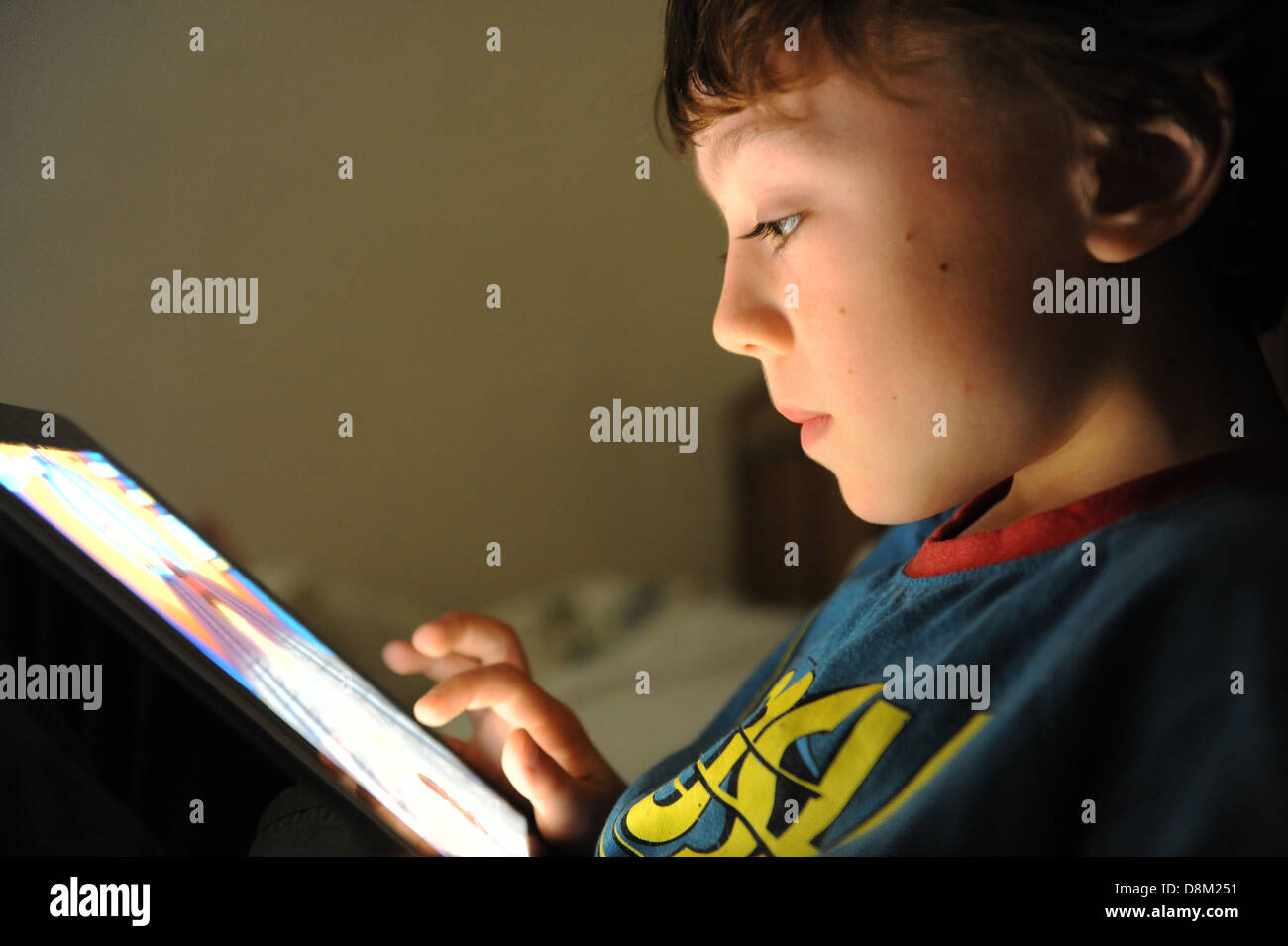 An 8 year old boy playing a computer game on his Apple IPAD in his ...