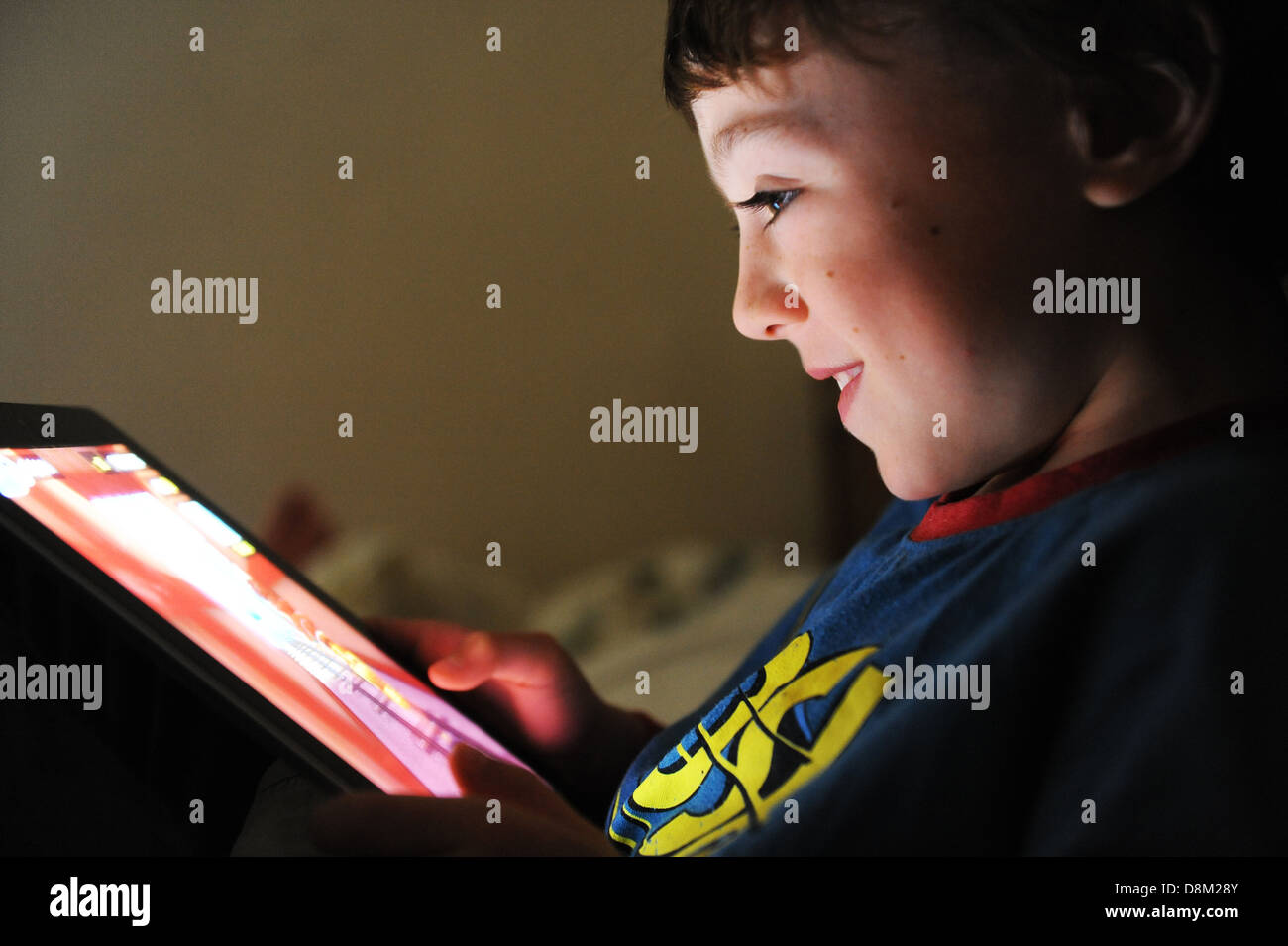 An 8 year old boy playing a computer game on his Apple IPAD in his ...