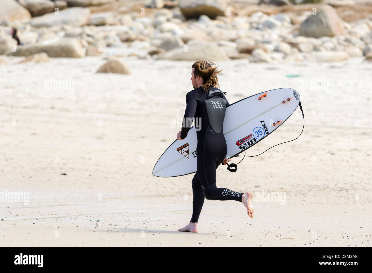 Surfing UK. A surfer running across the beach at Sennen Stock Photo - Alamy