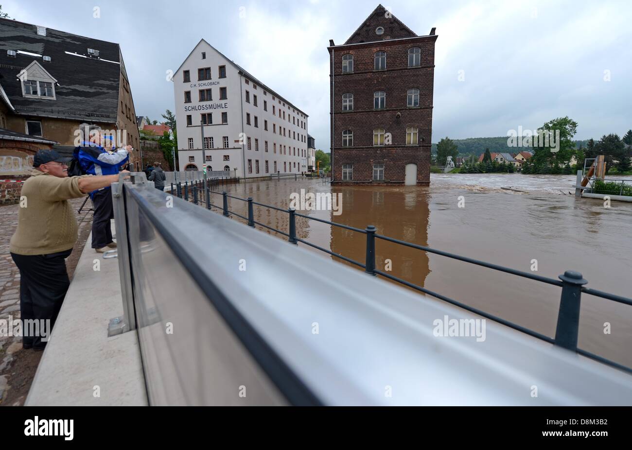 People look at the swollen Mulde River from a temporary flood wall in ...