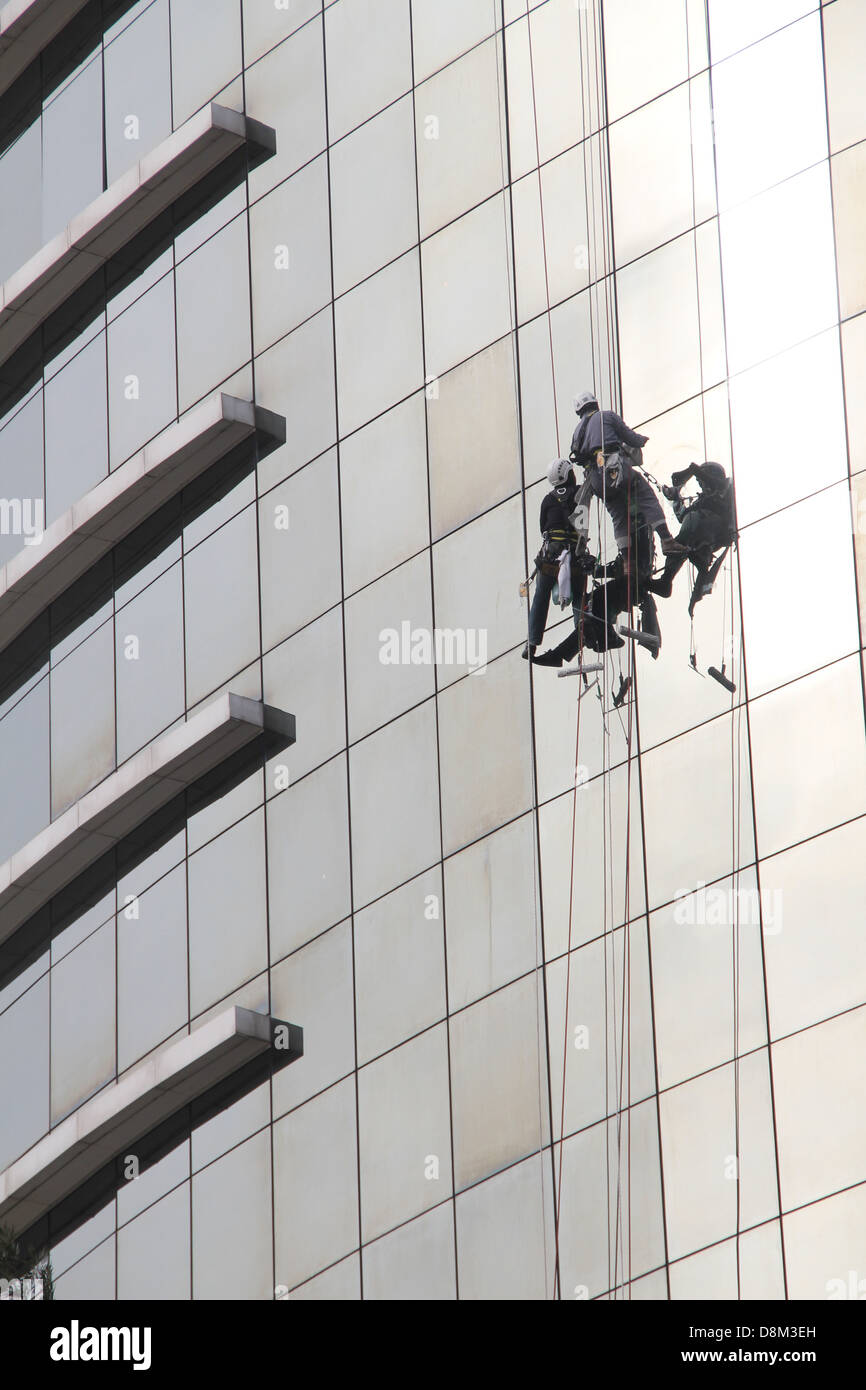 A window cleaner is seen working on the glass facade of an office tower ...