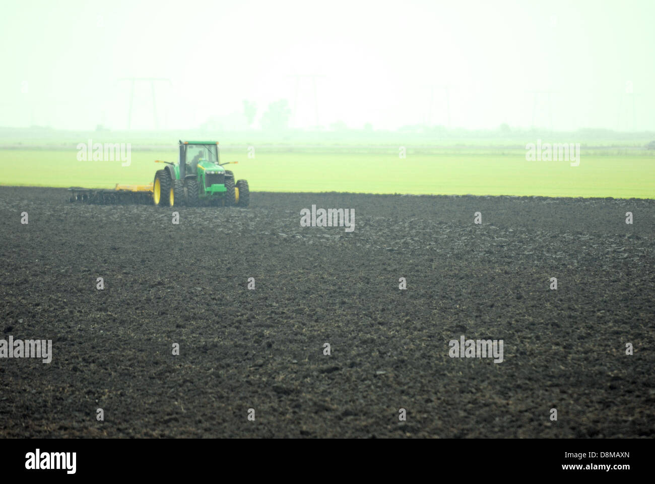 A farmer plowing the fields with a tractor in a rural countryside Stock ...