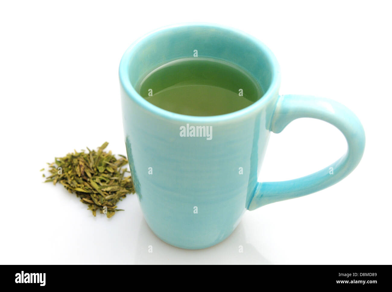 Cup of warm tea in blue mug with green tea leaves isolated on white ...
