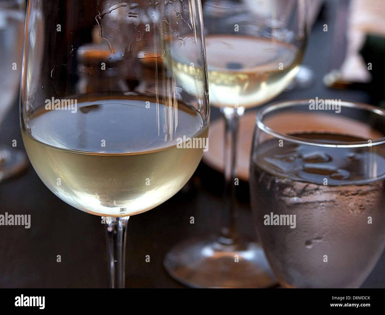 A clear glass filled with white wine, showcasing its pale golden color ...