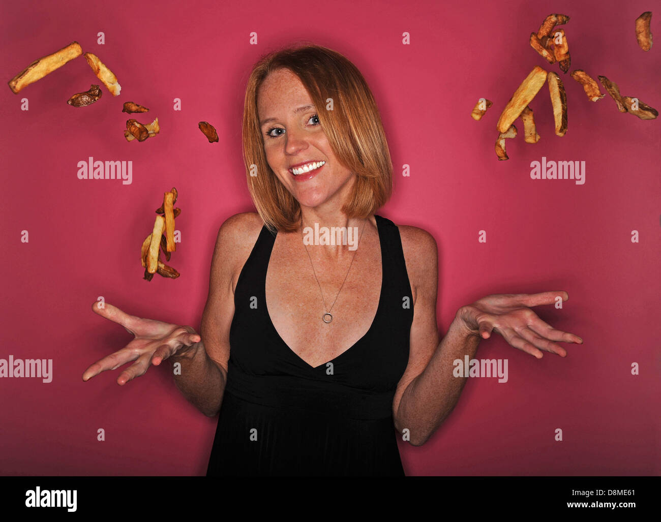 Beautiful woman on pink background throwing French fries in the air to ...