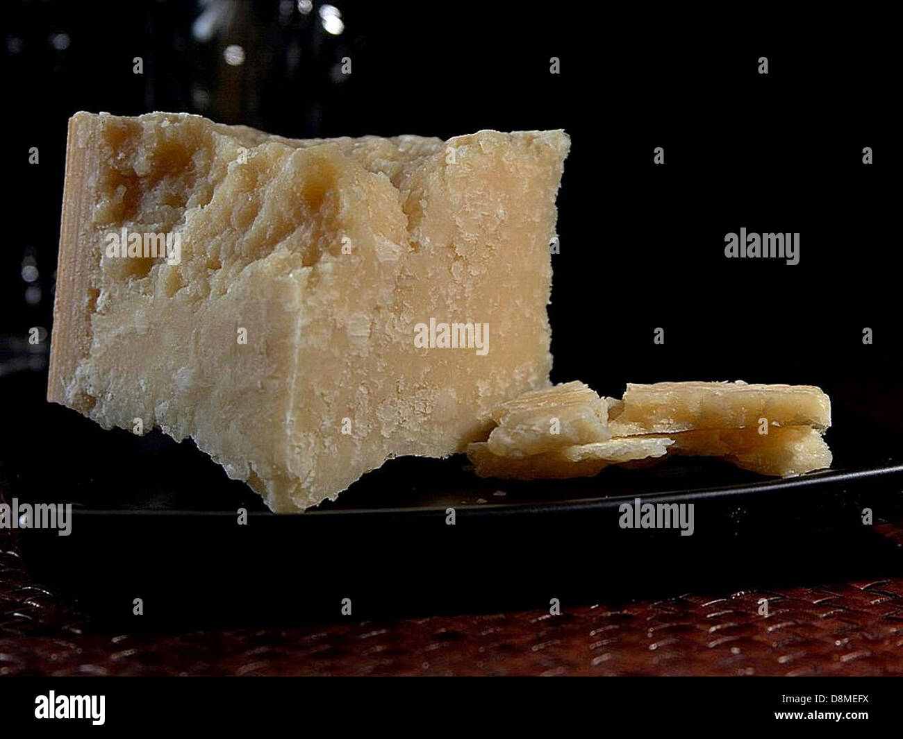 This image captures a block of Parmesan cheese, a hard, granular cheese ...