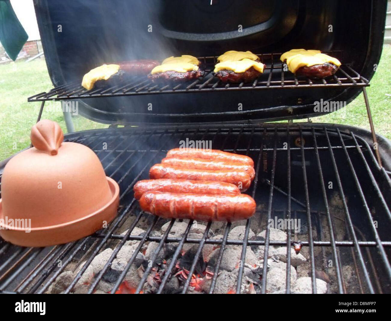 This stock photo shows a close-up of smoked burgers on a grill ...