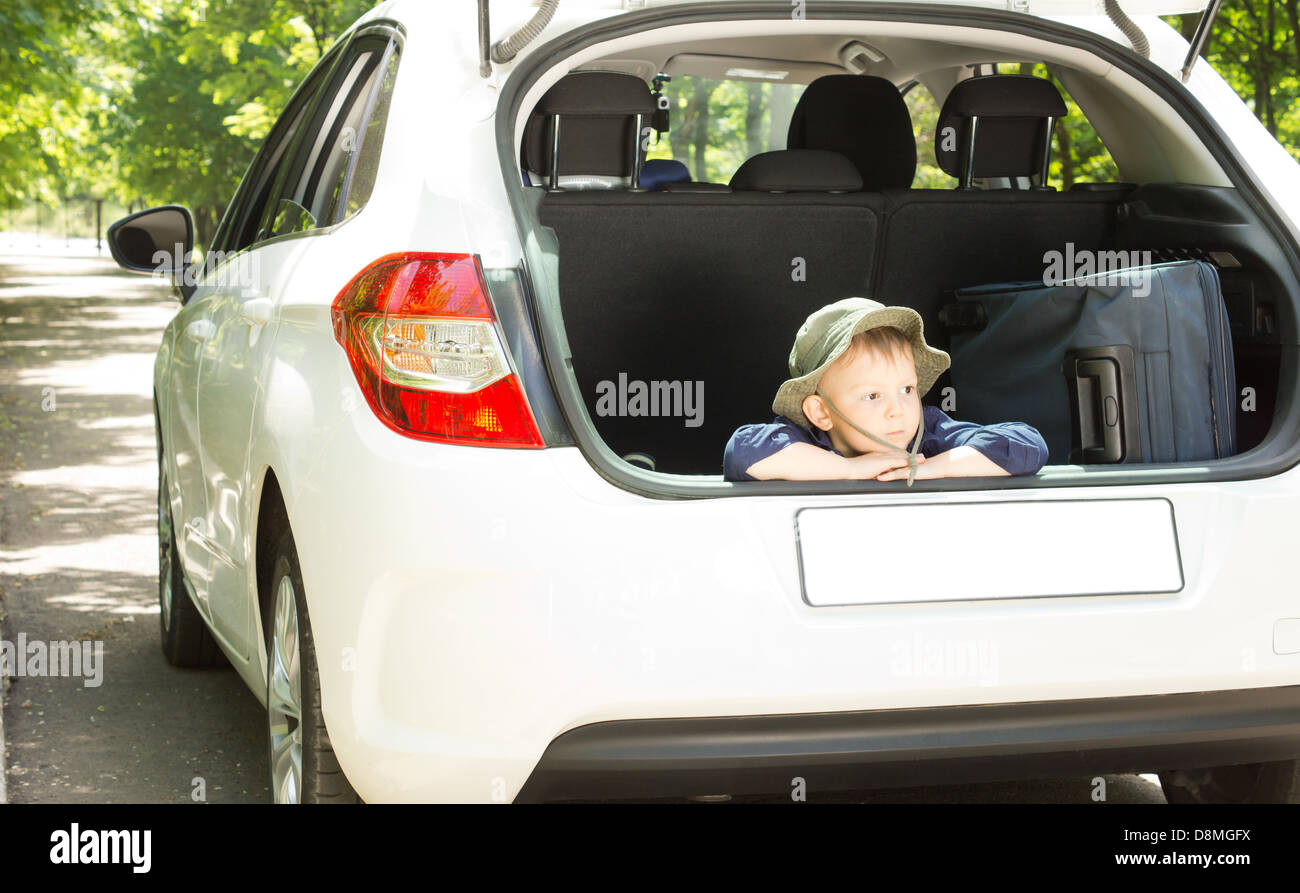 Little boy waiting in the back of a hatchback car with its boot open ...
