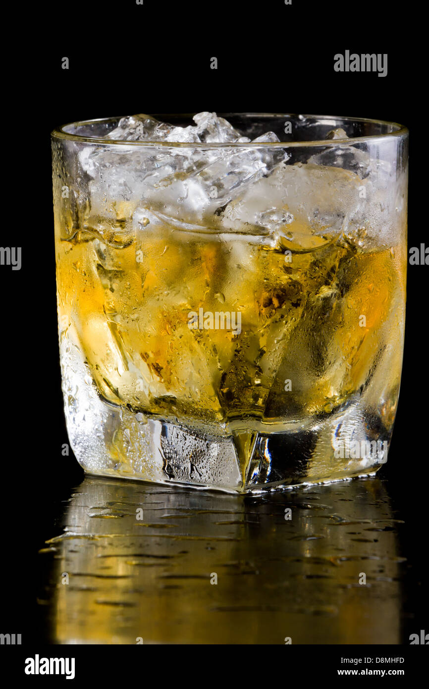 glass of whiskey over ice served on a dark bar Stock Photo - Alamy