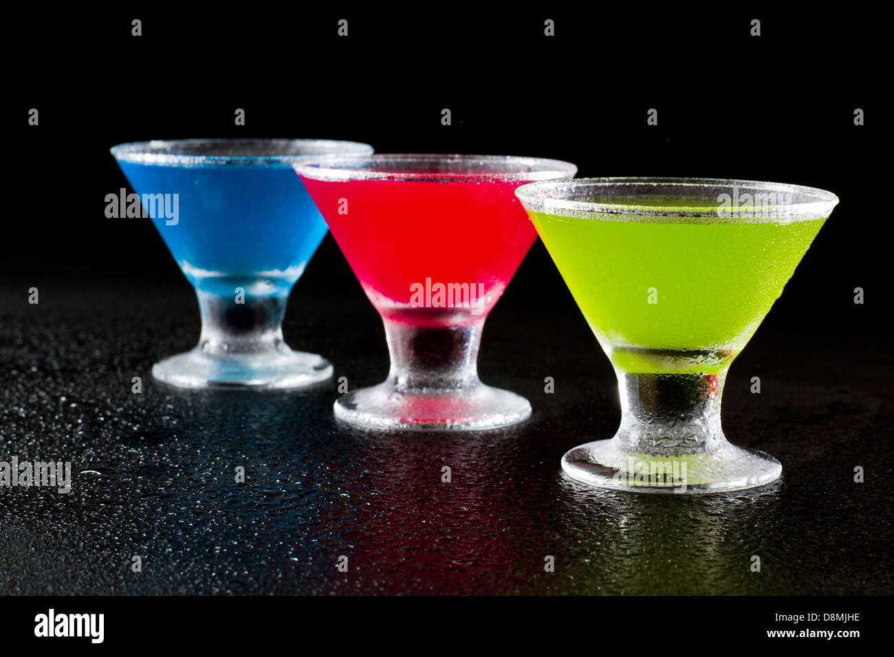 bright mini martinis served on a wet dark bar top for a dramatic effect ...