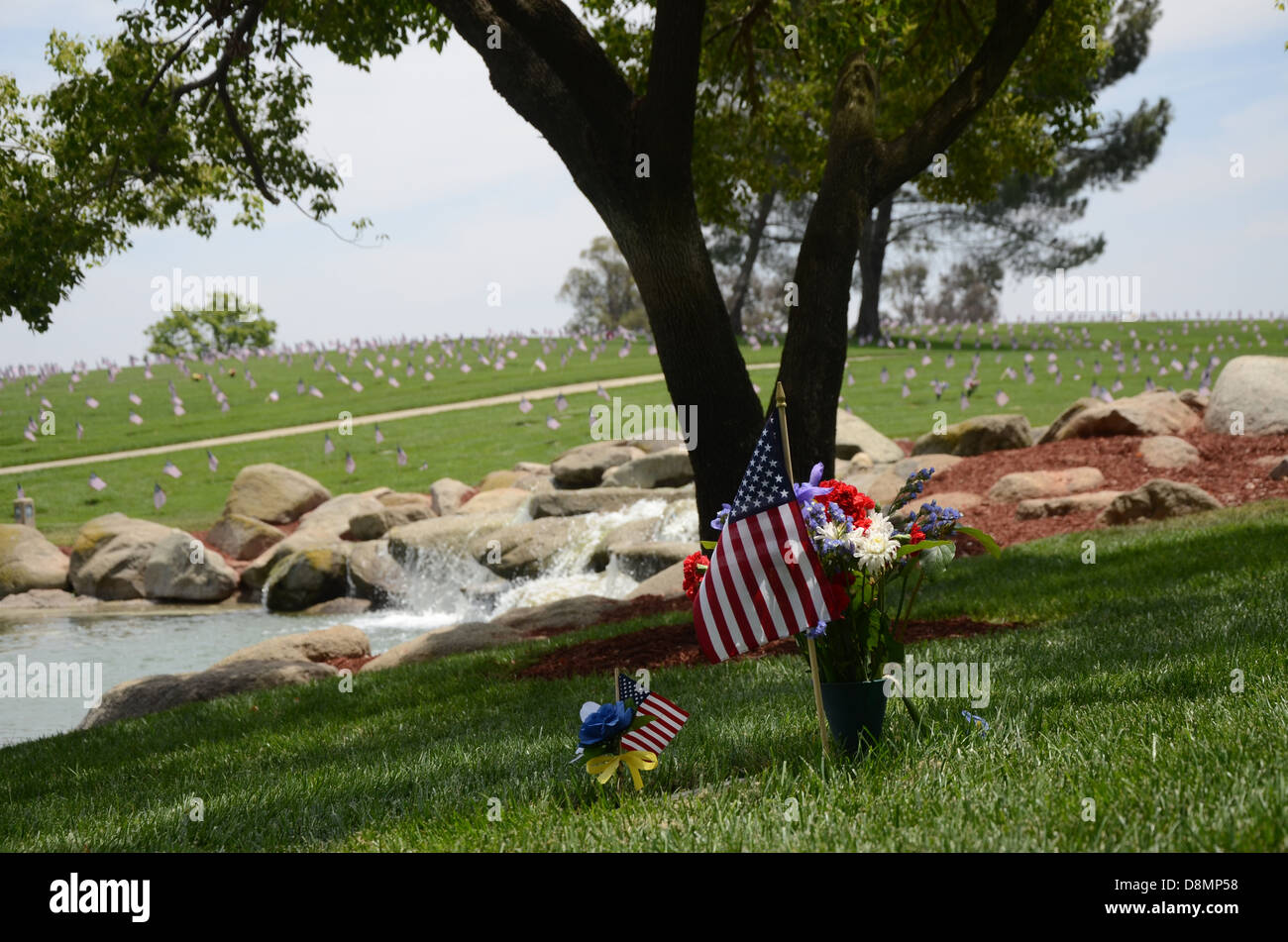 A stream cascades over rocks with Memorial Day Flags covering a ...