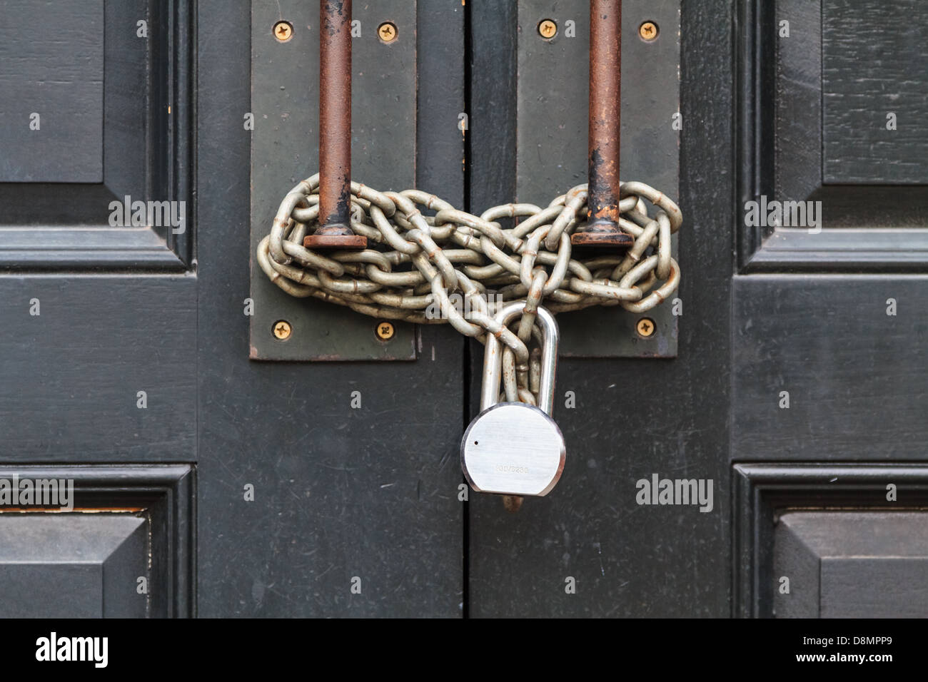 A black large door closed with a chain and a lock Stock Photo - Alamy