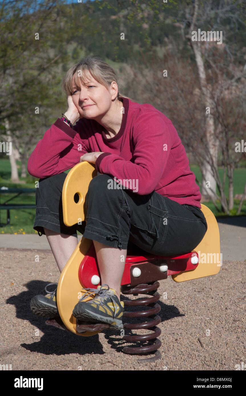 Woman sitting on playground riding toy Stock Photo - Alamy