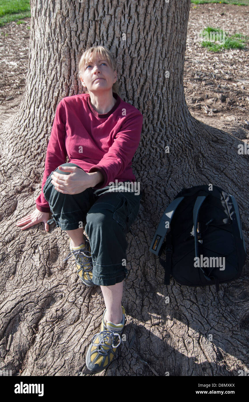 Woman sitting under a tree in thought Stock Photo - Alamy