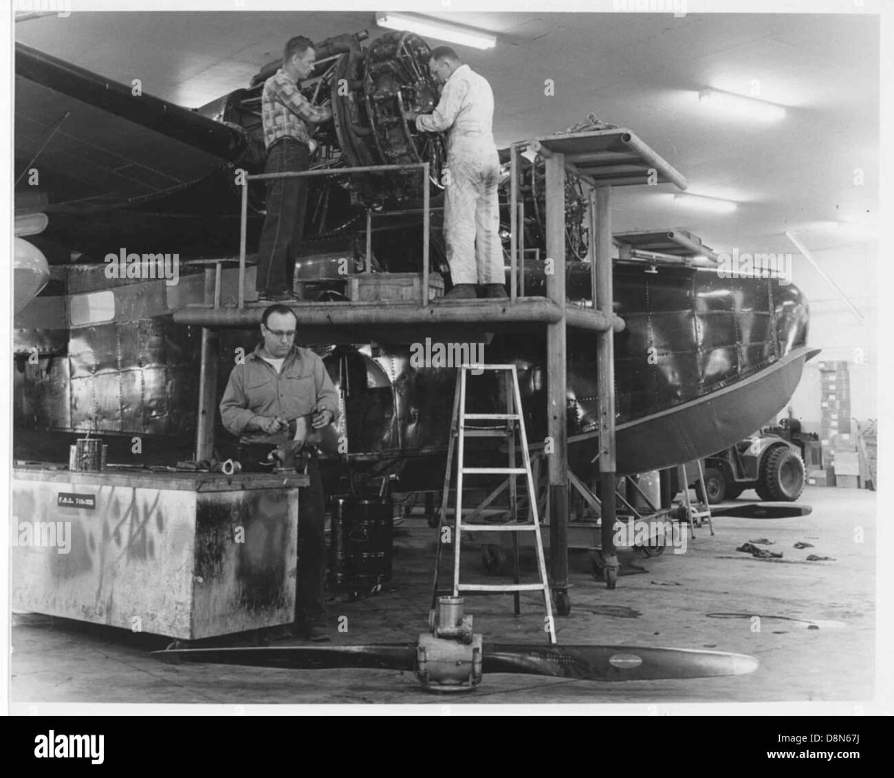A vintage photograph of aircraft maintenance, showcasing workers ...