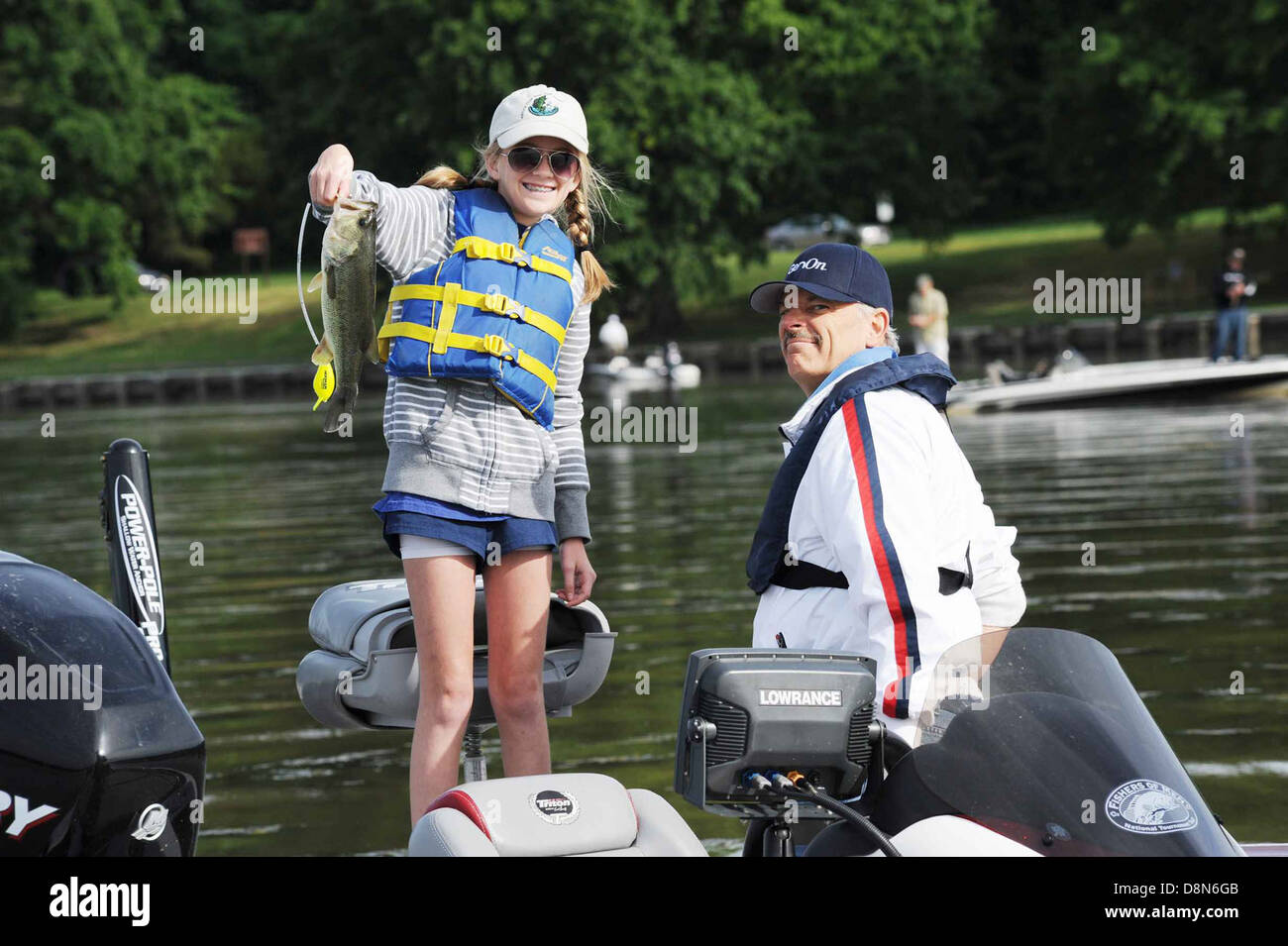 A child is holding up her freshly caught fish while standing in a boat ...