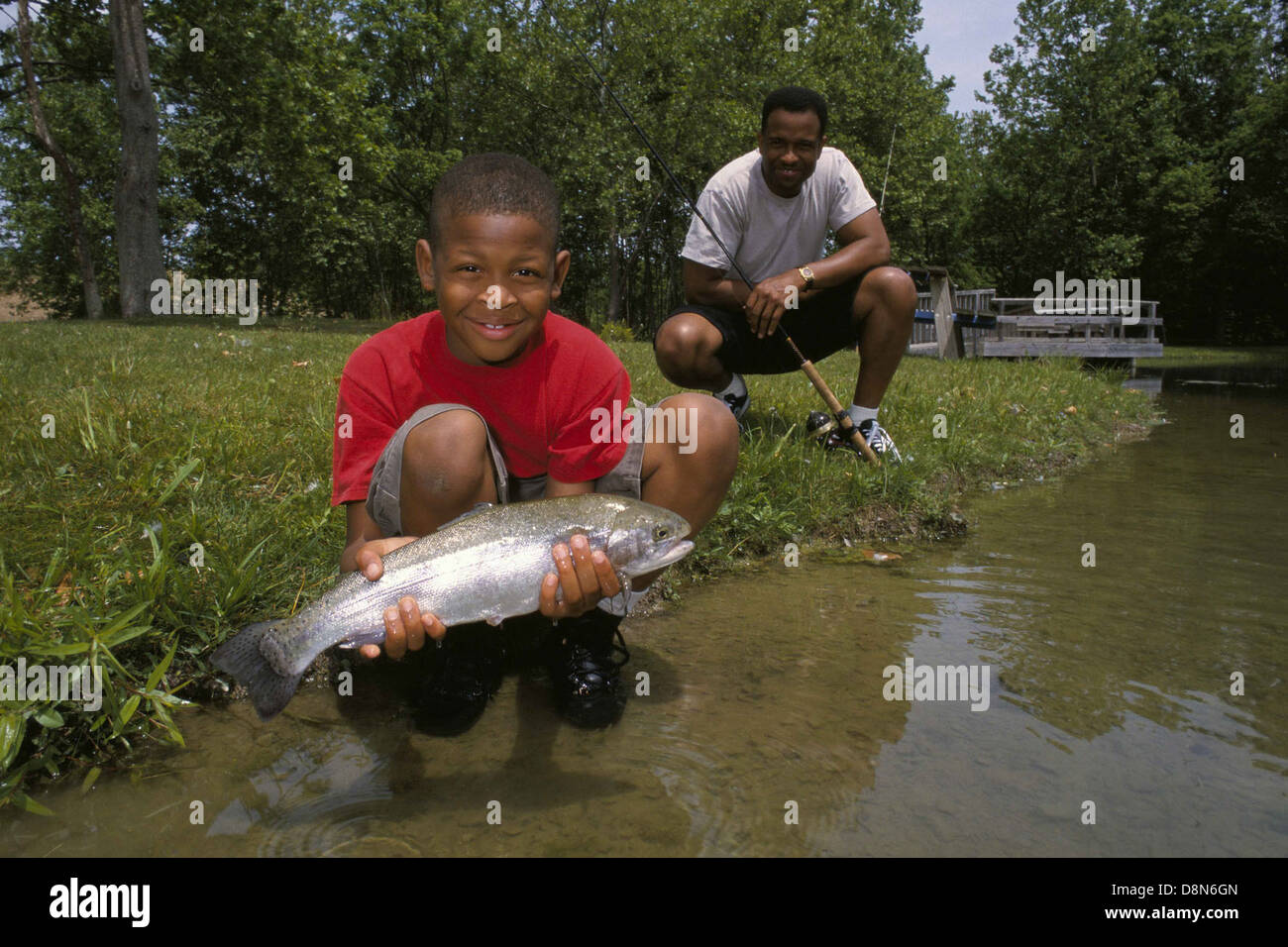 A father and son proudly pose for a photo while holding a fish they ...