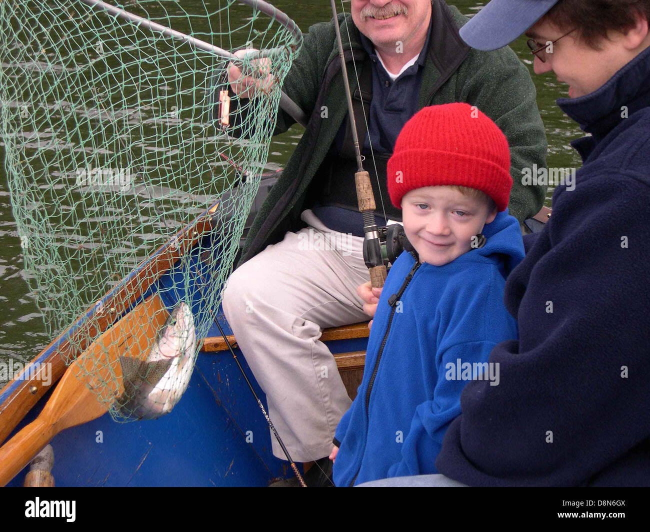 A young child proudly holds up the fish they caught, smiling for the ...