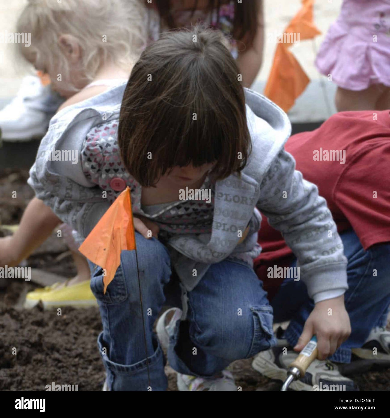 A young girl uses a trowel to dig a hole for plants in the pollinator ...