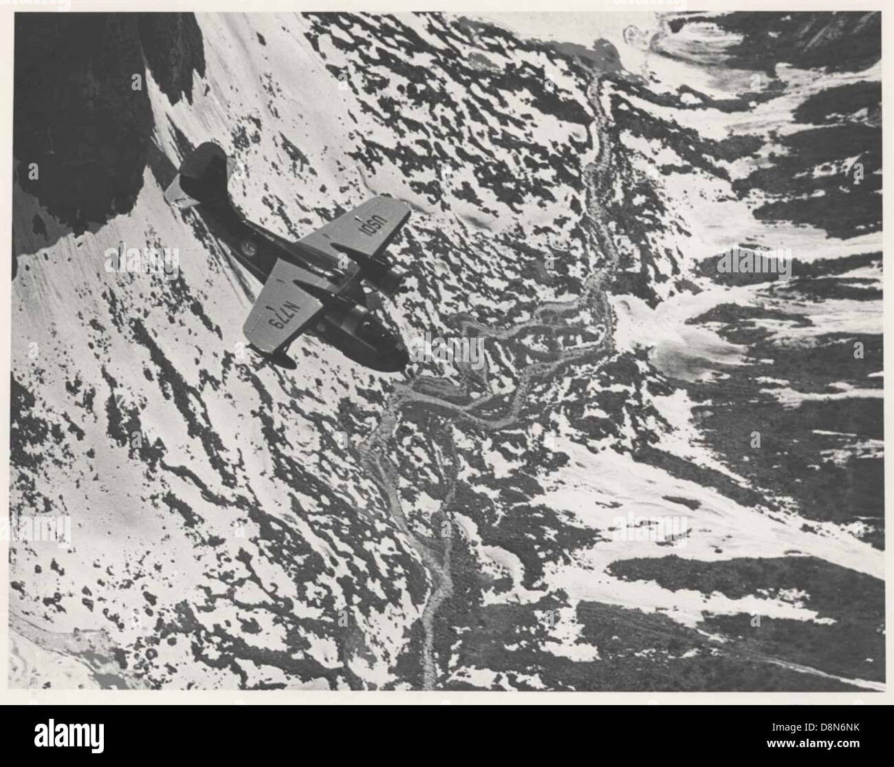 A black and white image capturing an aircraft mid-flight. This ...