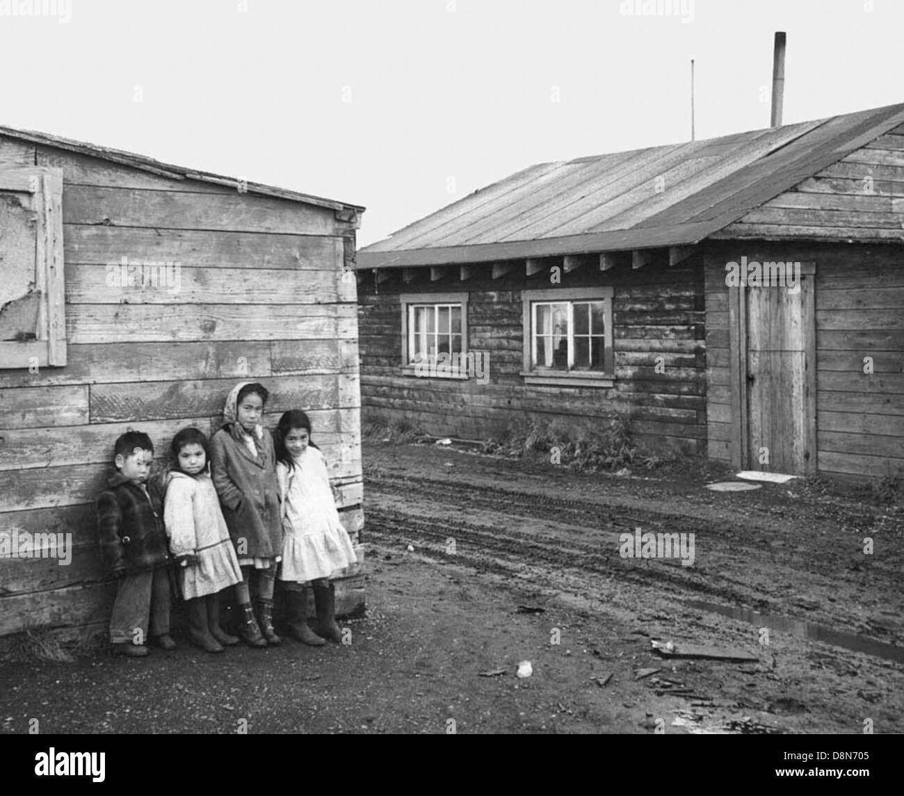 A photo showing children standing near traditional Native Alaskan homes ...