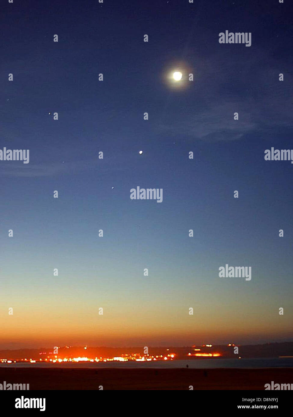 This image captures a peaceful evening scene with a sunset, the moon ...