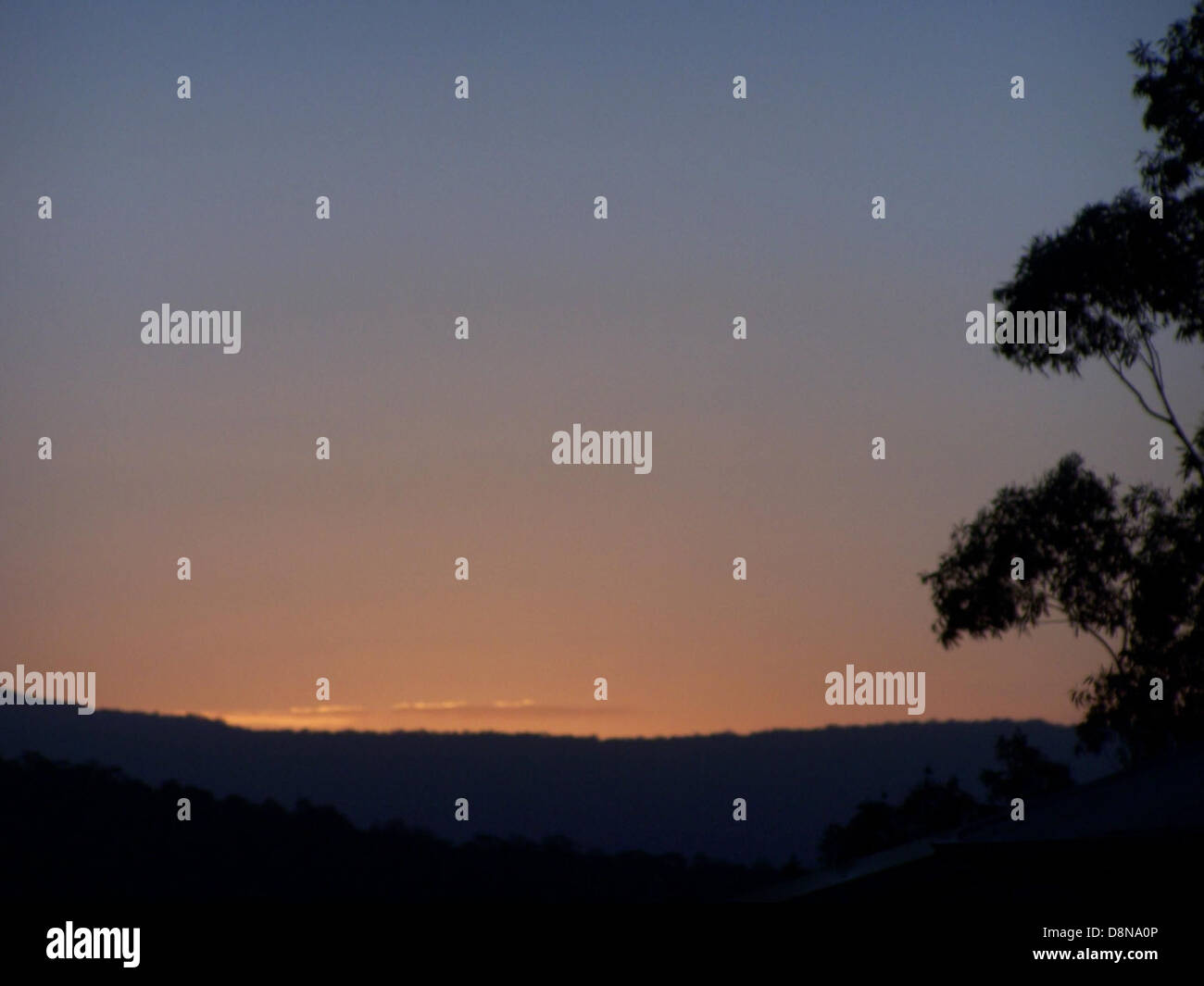 The sunset view from a hilltop shows the sky painted in warm colors ...
