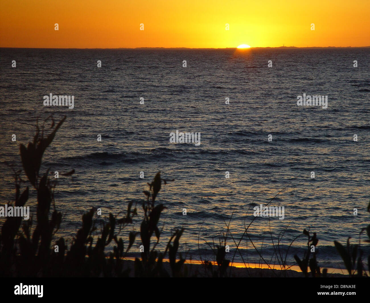 Sunset over island Stock Photo - Alamy
