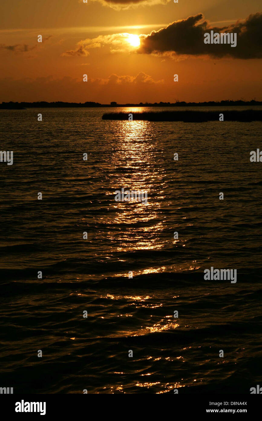 A serene sunset over a body of water, with the sun casting warm colors ...