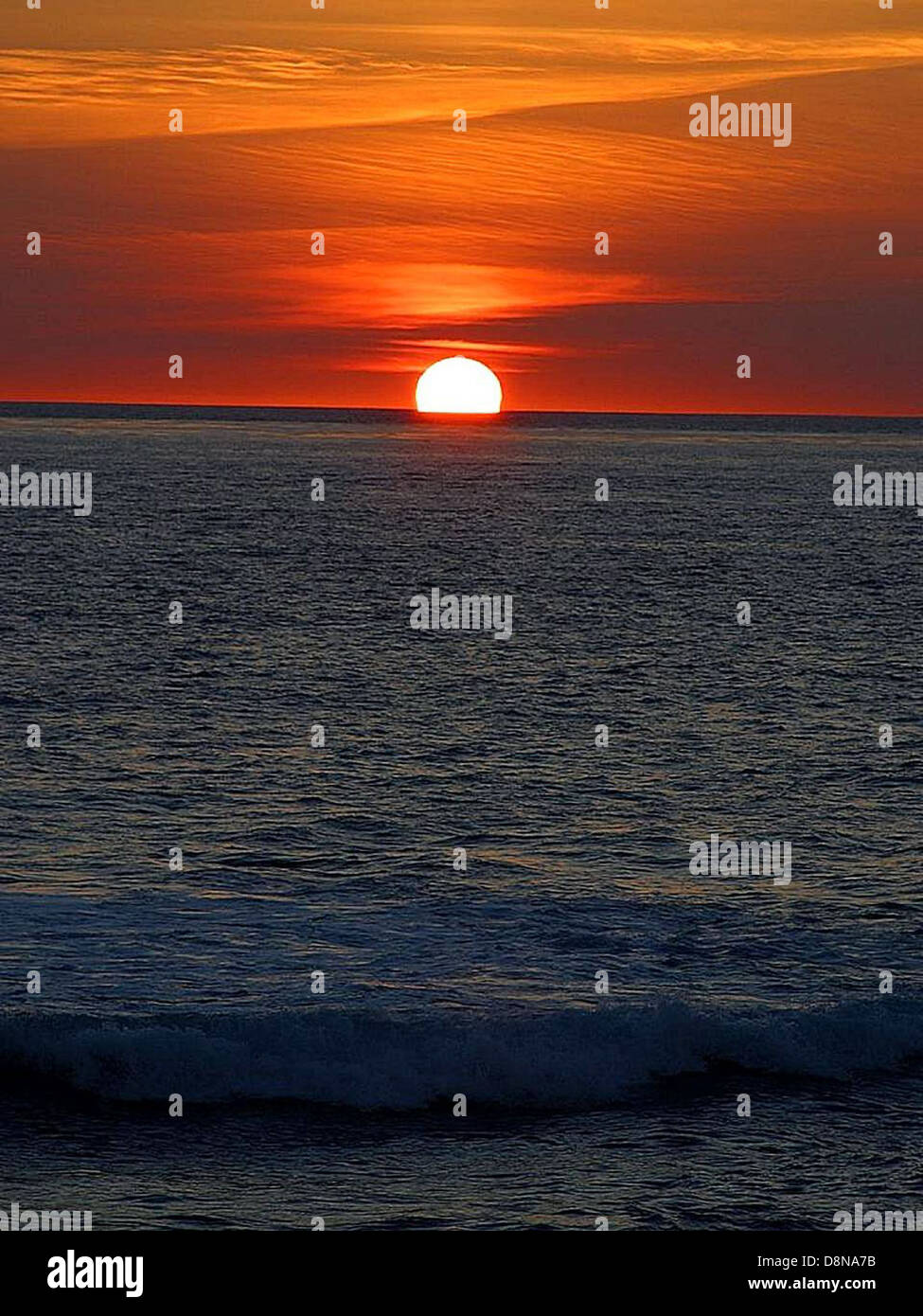 A breathtaking view of the ocean at sunset, with the sun dipping below ...