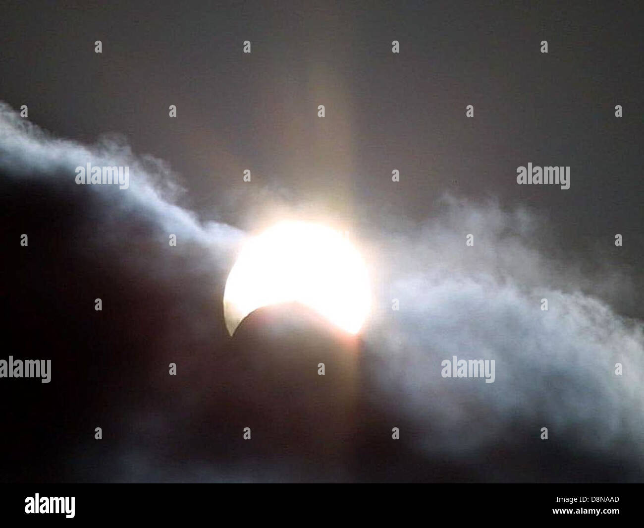 A captivating image of the sun partially obscured by clouds during an ...