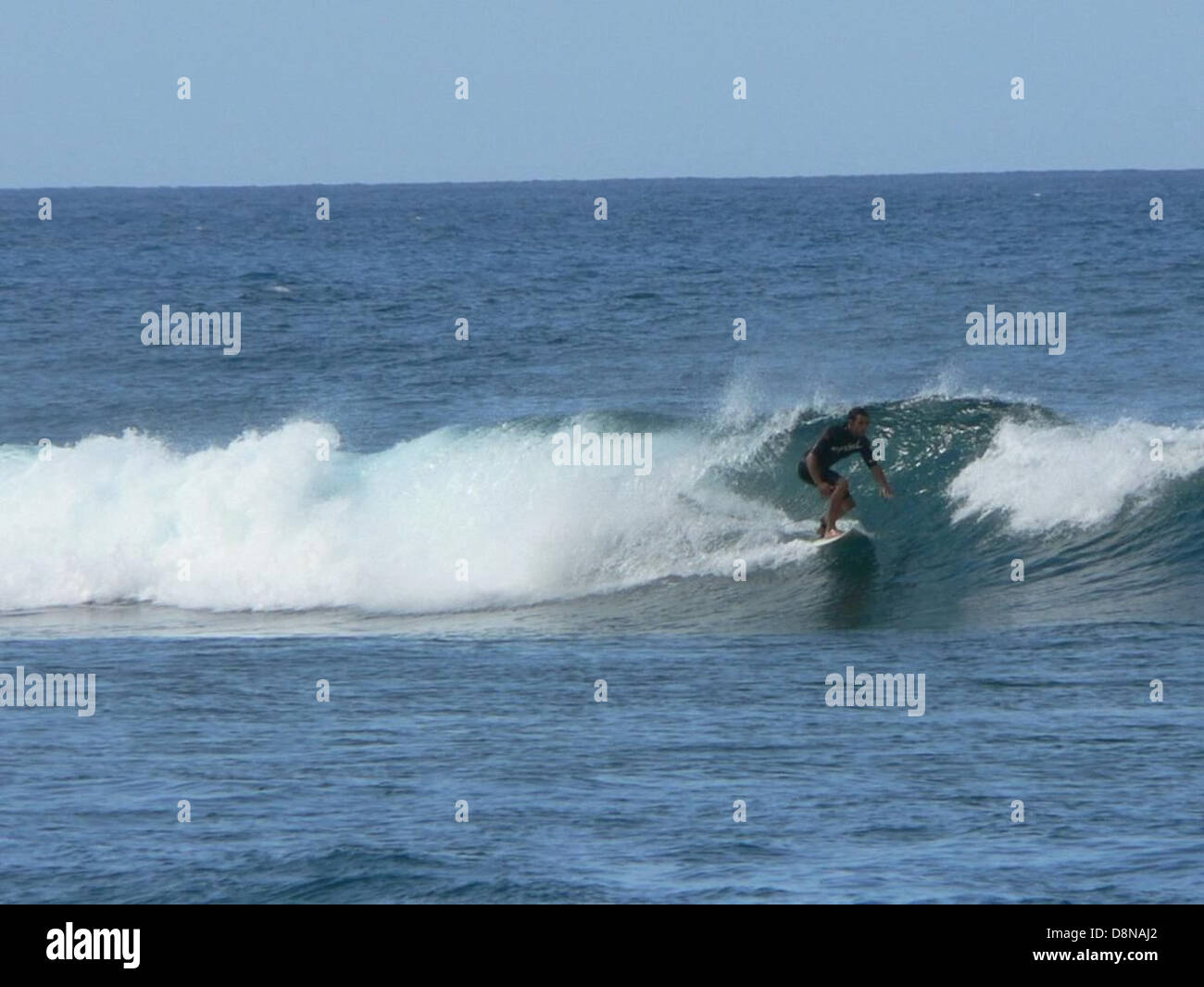 A surfer rides a large wave, demonstrating skill and balance in the ...