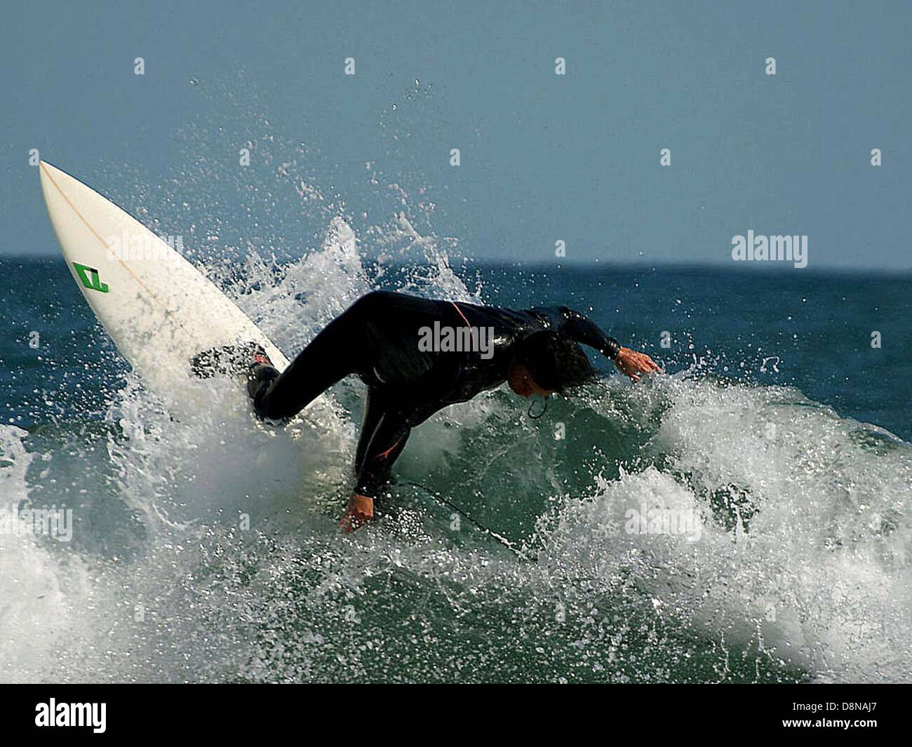 A surfer is captured mid-air, jumping out of the water on their board ...