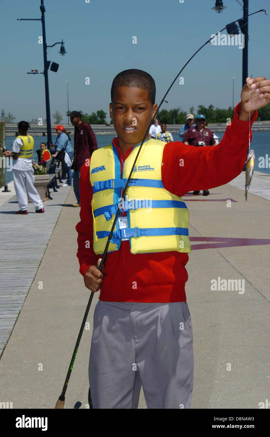 A young boy happily holding a fish he caught, showcasing his enjoyment ...
