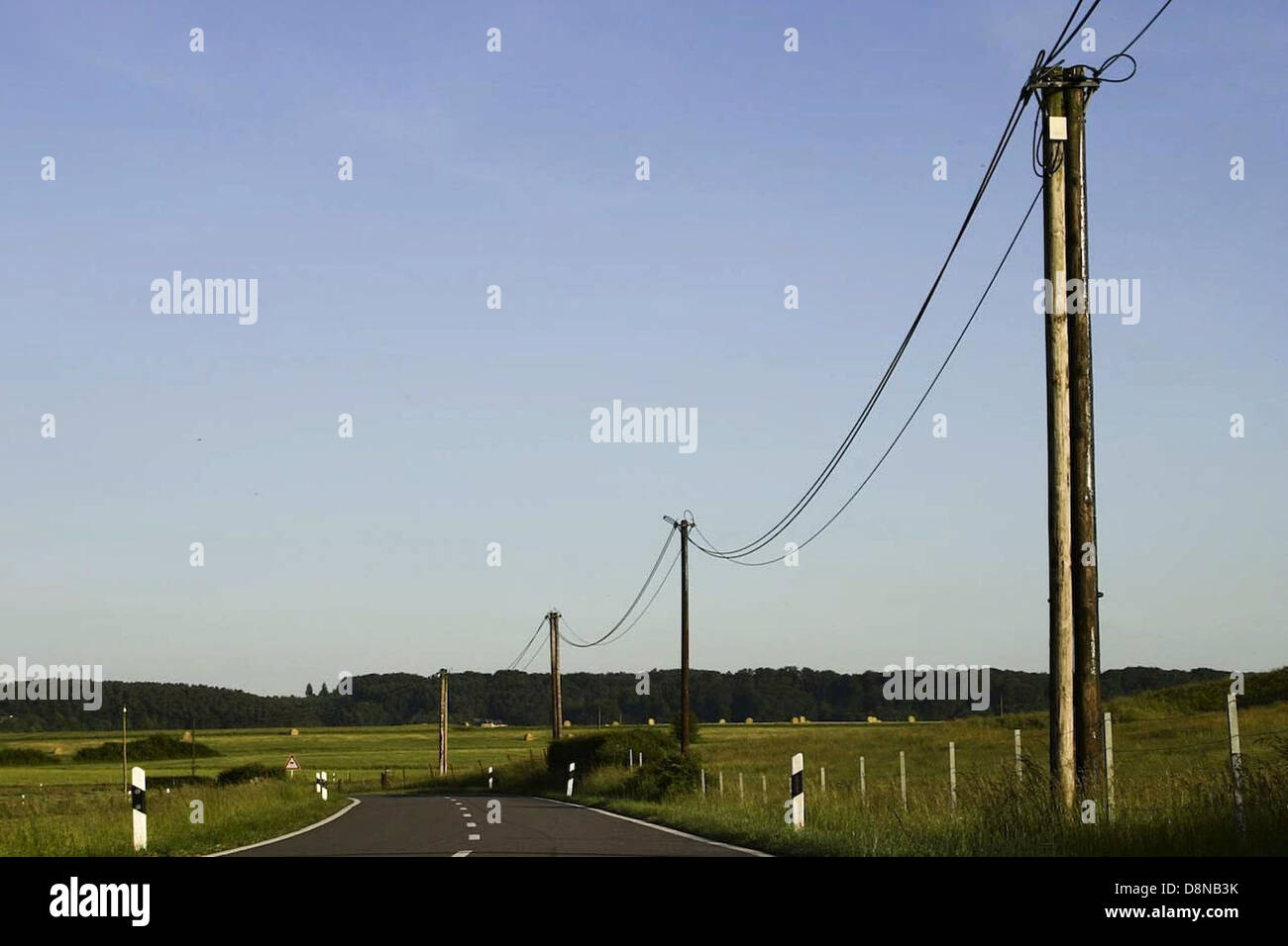 A telephone line running along a rural road, supported by wooden ...