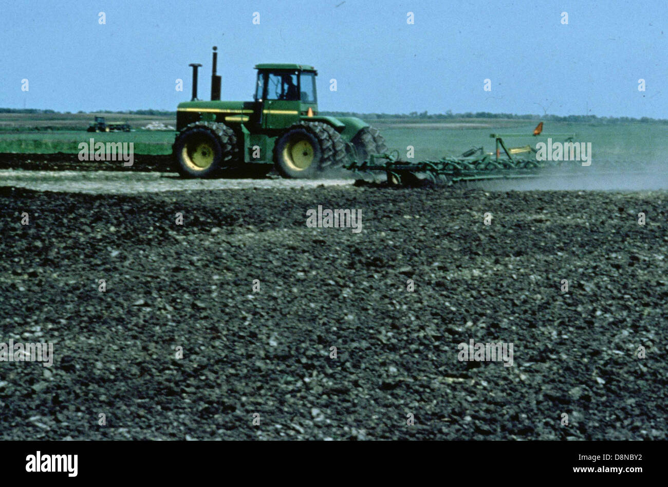A tractor is plowing cultivated fields, preparing the land for planting. This agricultural ...