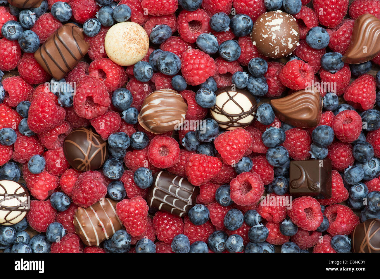 Raspberries, blueberries and chocolates pattern from above Stock Photo ...