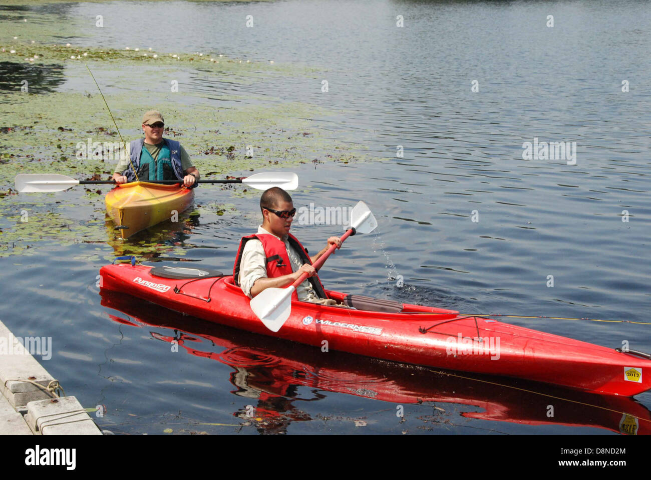 Two young men enjoying a relaxing canoe ride on a calm river. The ...