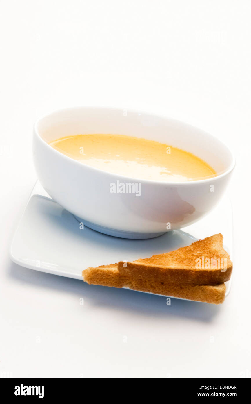 A bowl of tomato soup and toast is seen against a white background ...